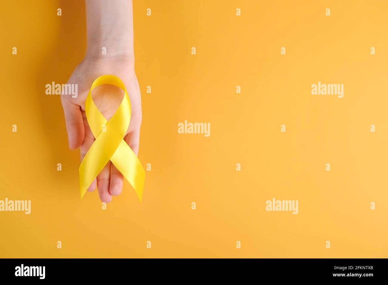 Woman's hand holding yellow ribbon - bladder, liver and bone cancer ...