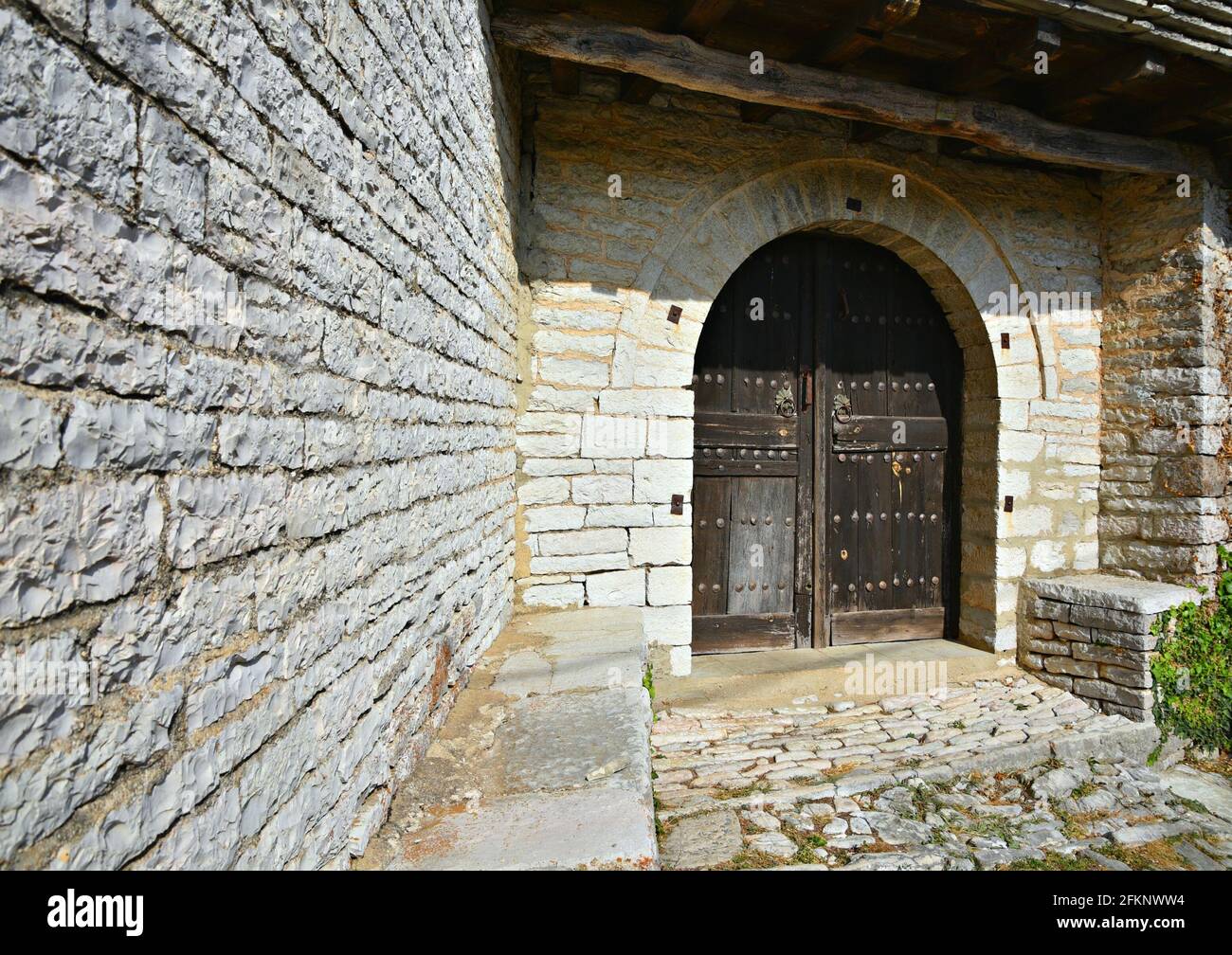 Rural stone house facade with a vintage antique door in Monodendri, a ...