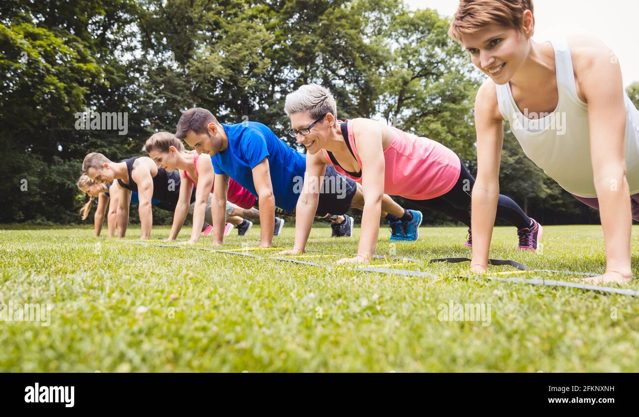 Fitness group practising push-ups in park Stock Photo - Alamy