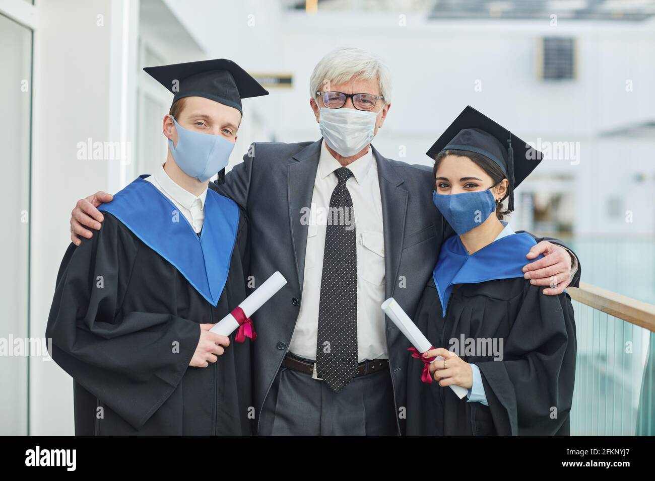 Waist up portrait of two college graduates wearing masks while posing ...