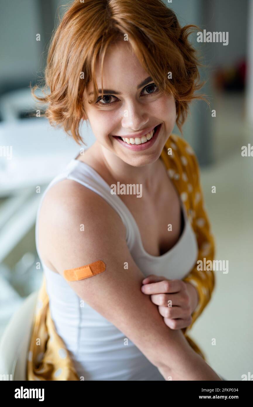 Happy woman with plaster on arm after vaccination in hospital, looking ...