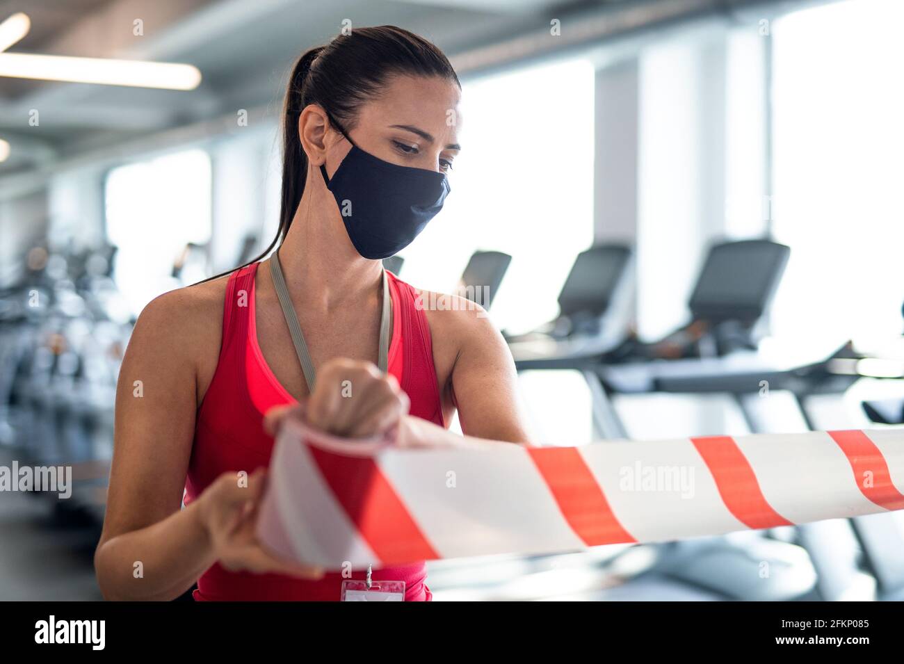 Fitness instructor with face mask marking safe distance in gym ...