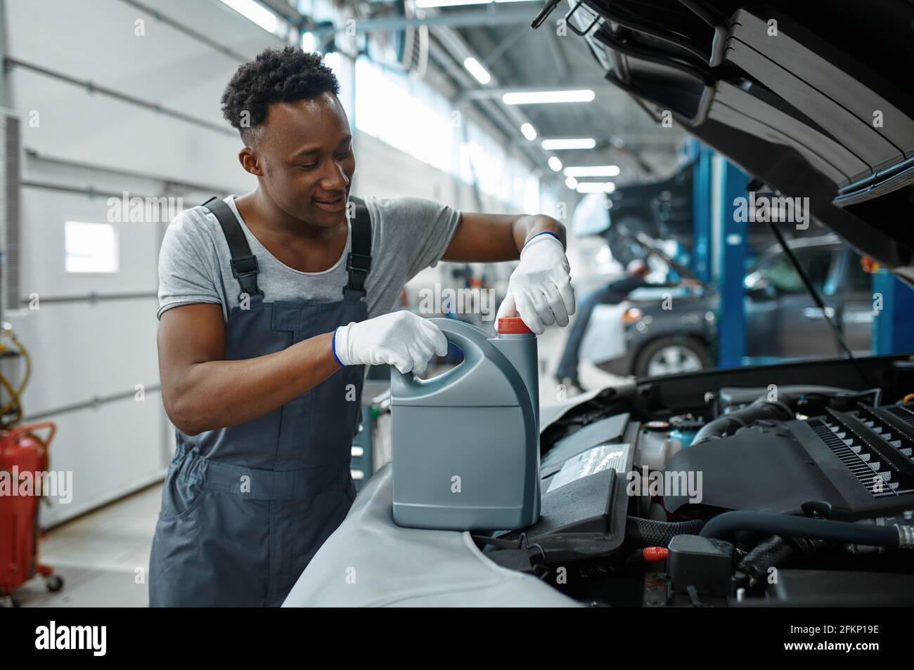 Male worker changes oil in engine, car service Stock Photo - Alamy