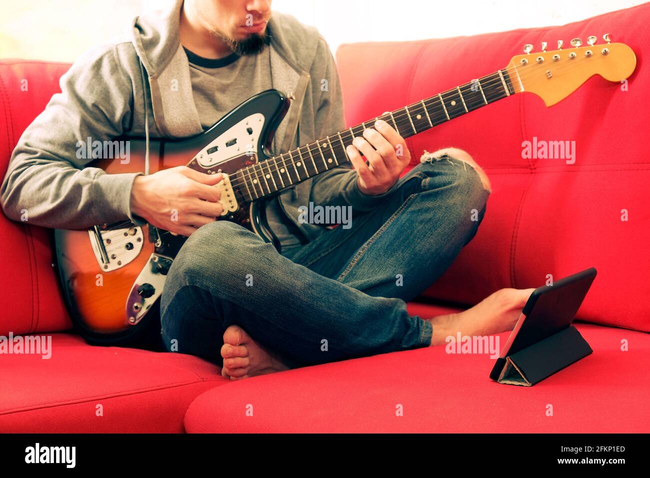 Casual young man in ripped jeans, playing sunburst offset electric ...