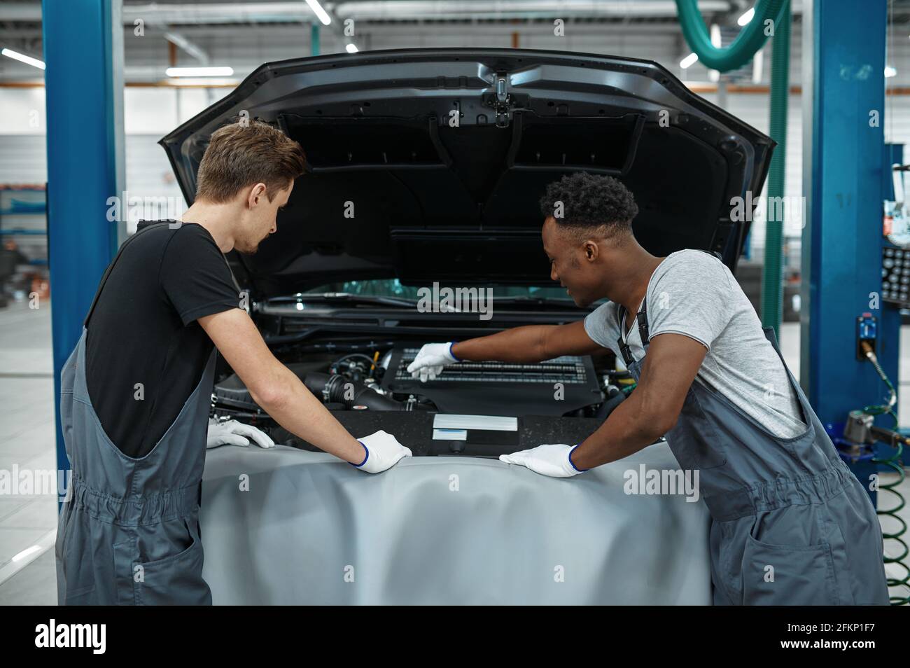 Two male mechanics checking motor, car service Stock Photo - Alamy