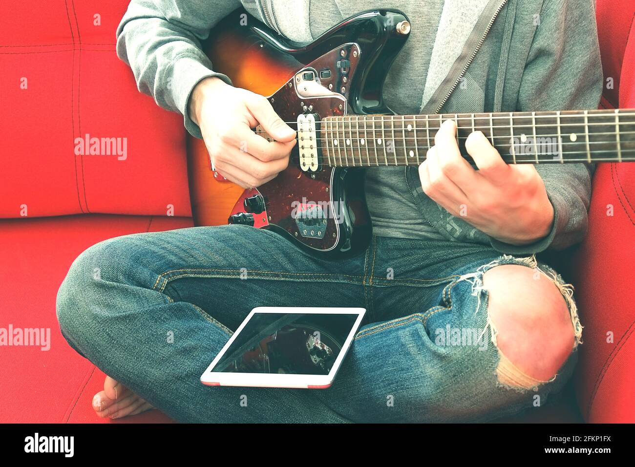 Casual young man in ripped jeans, playing sunburst offset electric ...