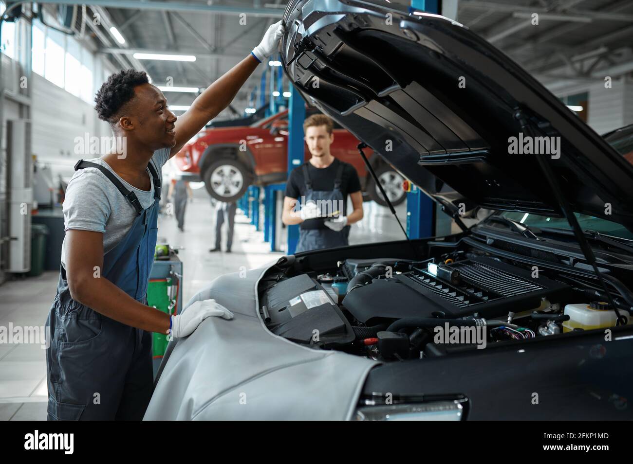 Two male workers inspects engine, car service Stock Photo - Alamy