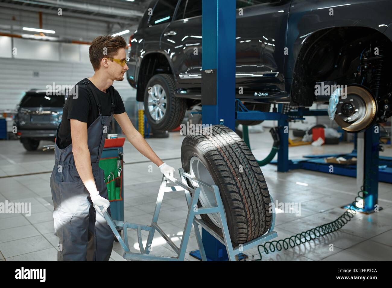 Mechanic fixes problem with wheel, car service Stock Photo - Alamy