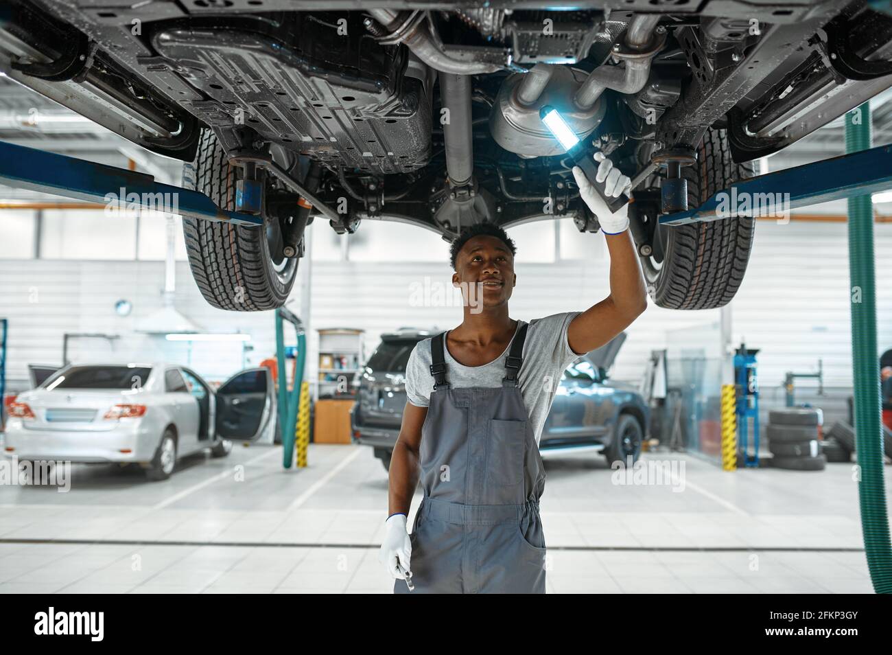 Male mechanic checks car suspension, auto service Stock Photo - Alamy