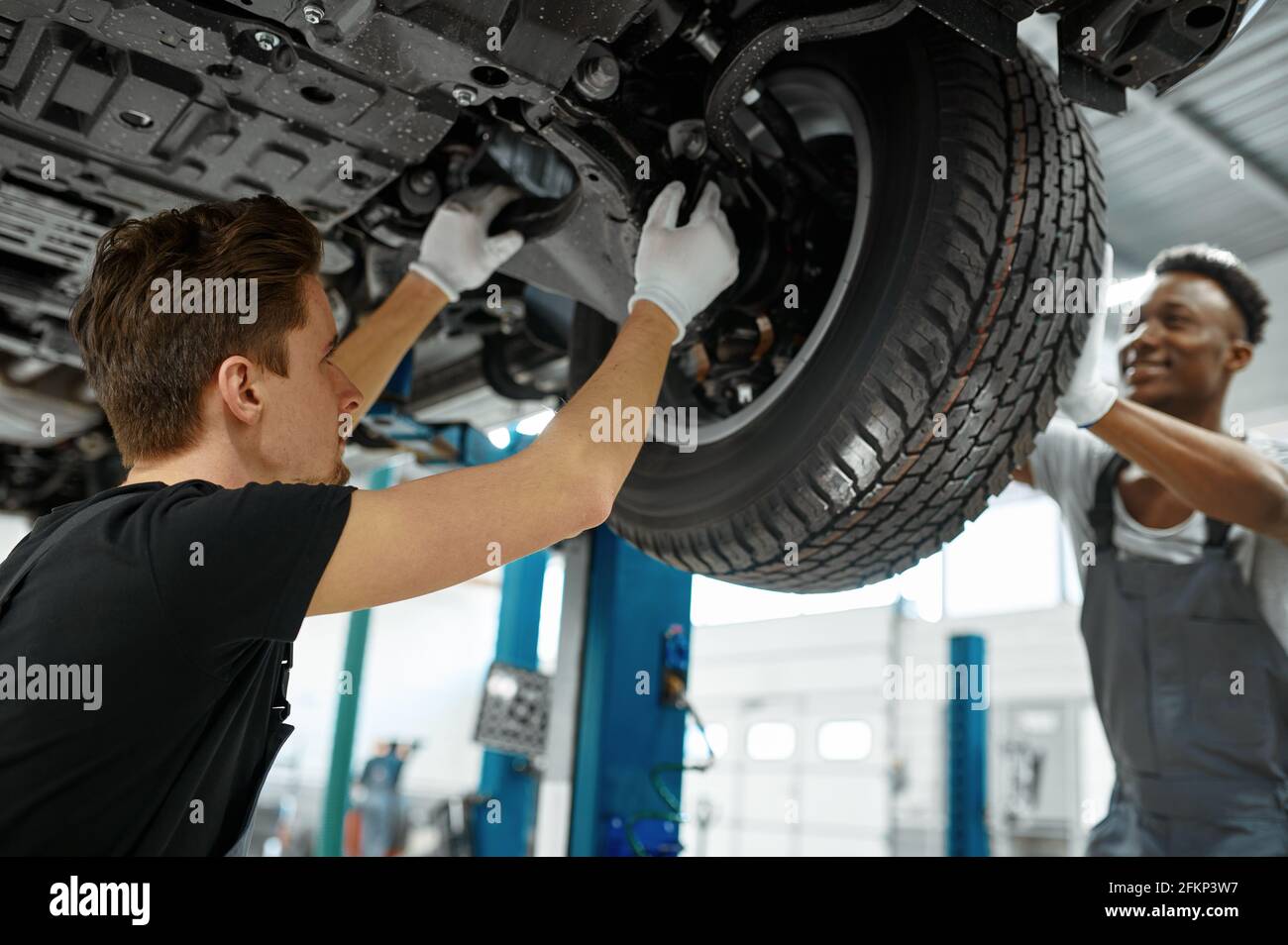 Two male workers fixes wheel, car service Stock Photo - Alamy