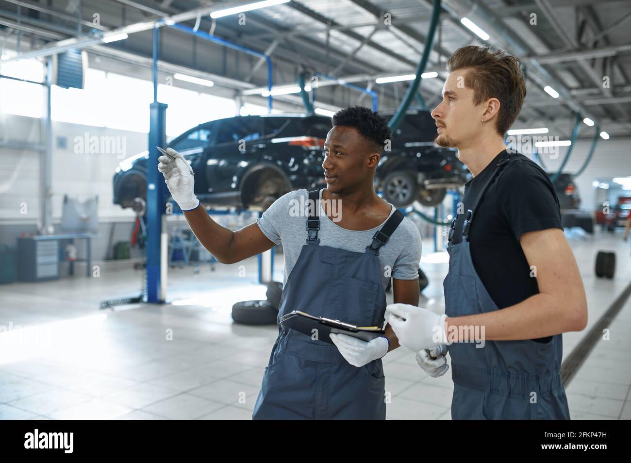 Two male mechanics talking in car service Stock Photo - Alamy