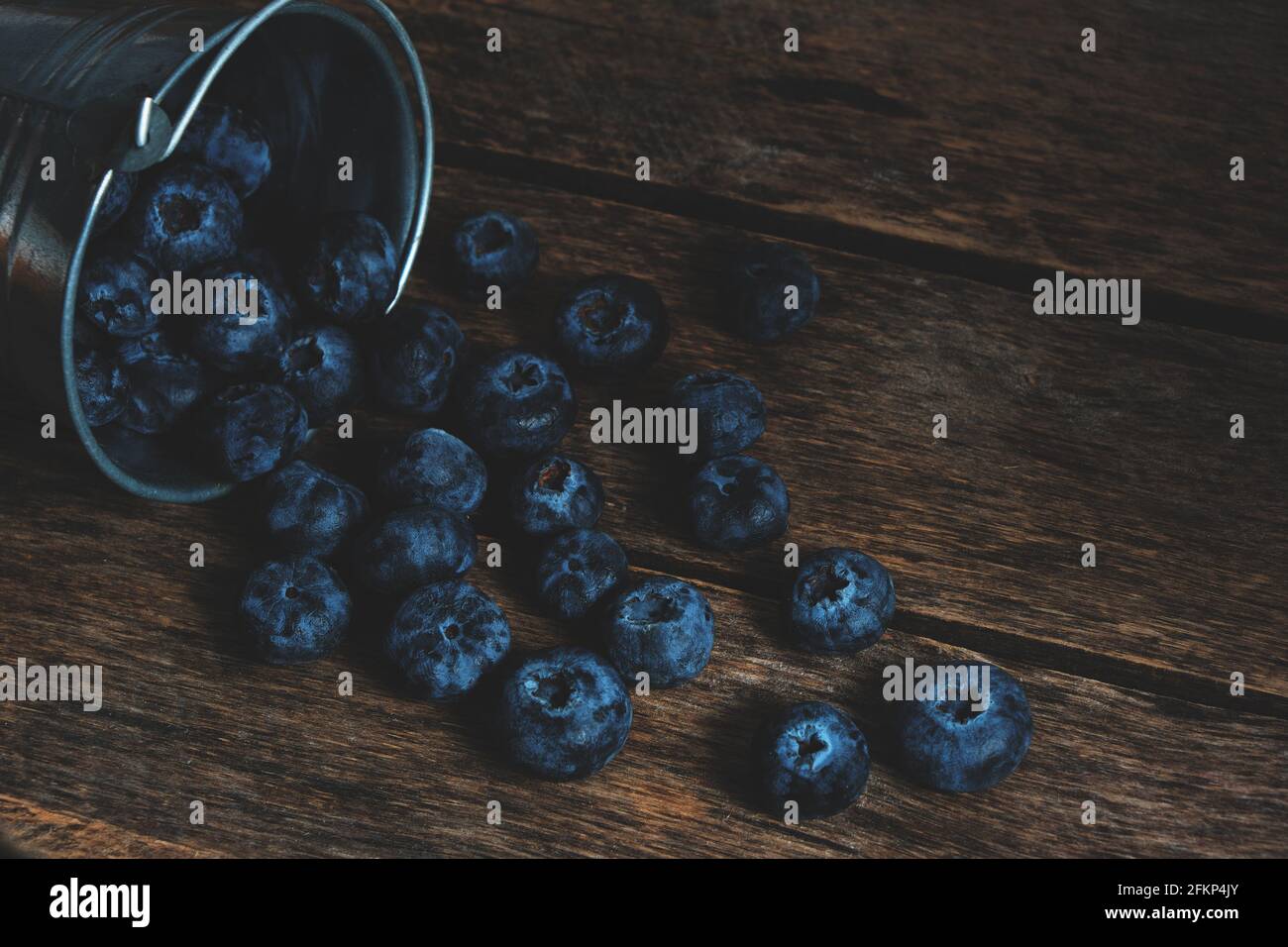 Blueberry berries spilled from metal bucket onto wooden table Stock ...