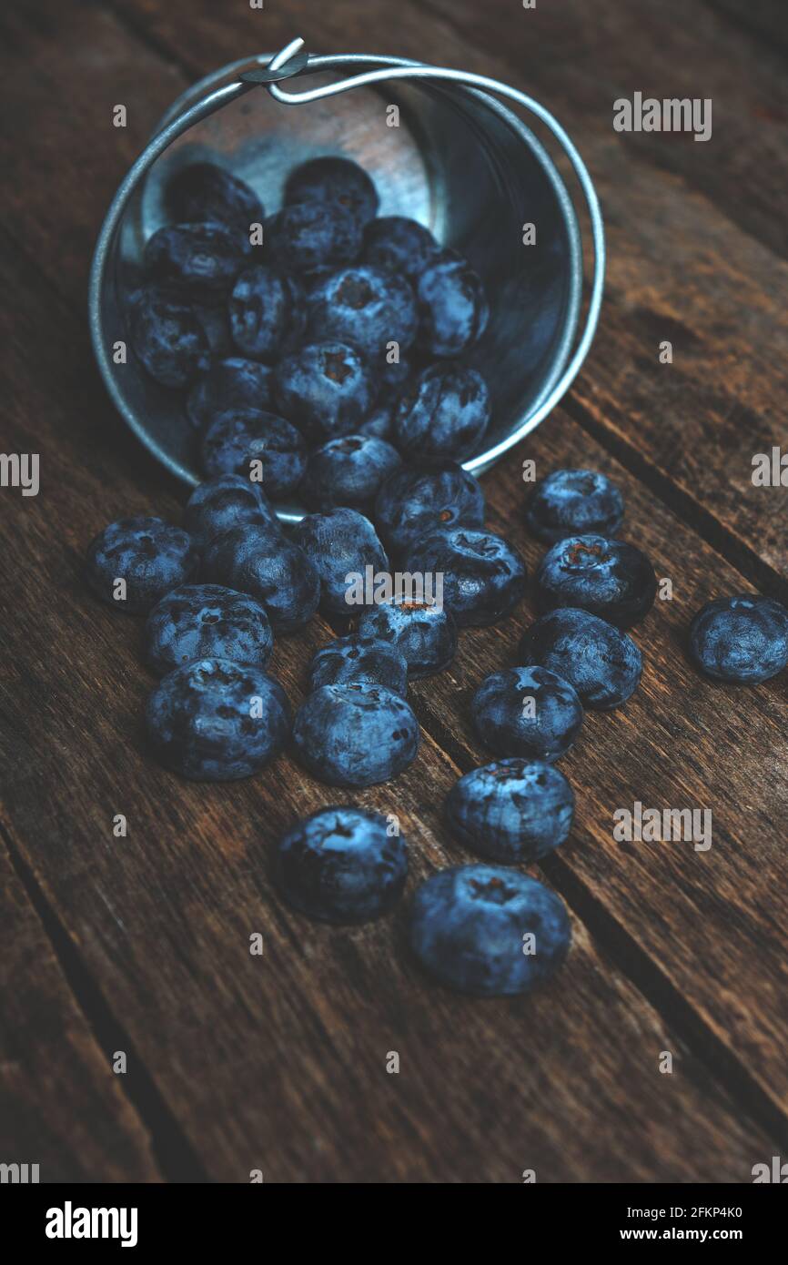Blueberry berries spilled from metal bucket onto wooden table Stock ...