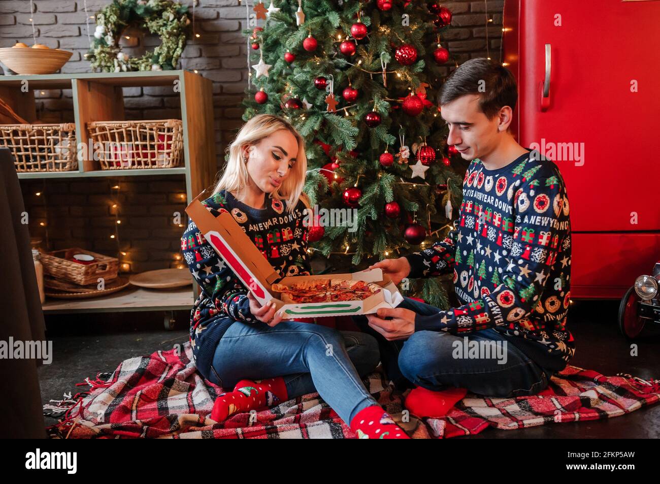 A guy with a girl in a sweater and jeans eating pizza Stock Photo - Alamy