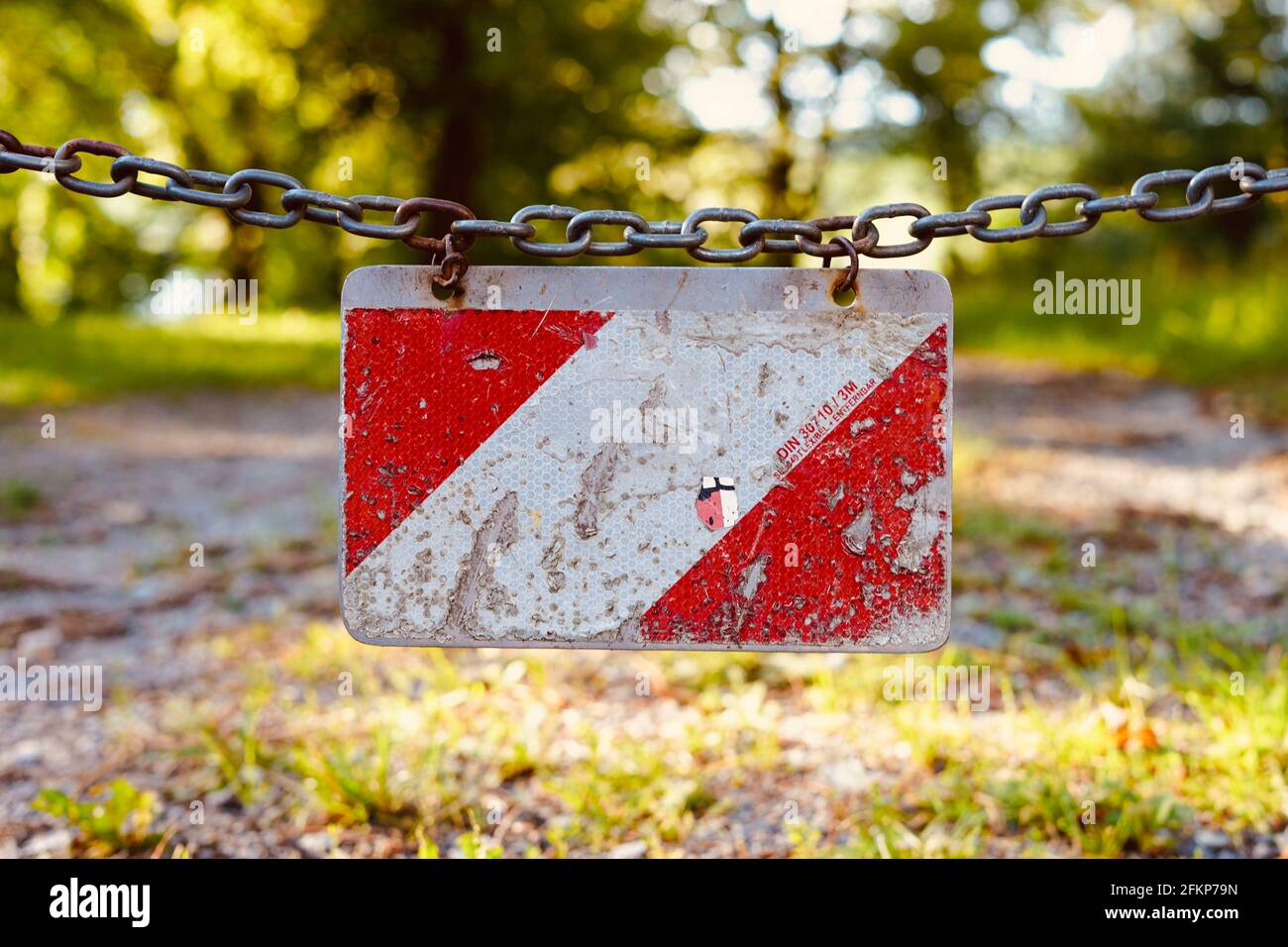 Closeup shot of a red and white damaged warning sign hanging on a chain ...