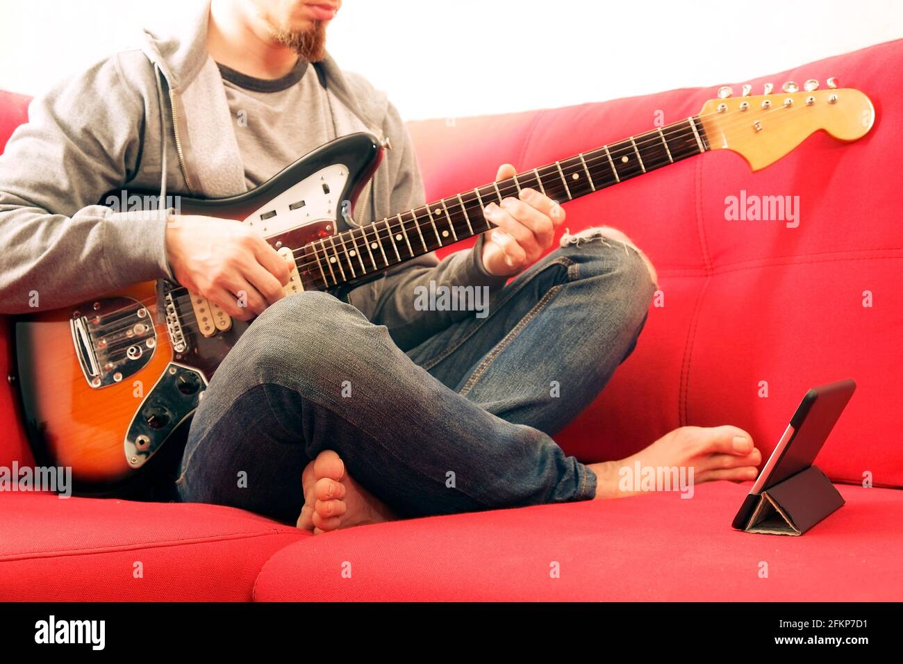Casual young man in ripped jeans, playing sunburst offset electric ...