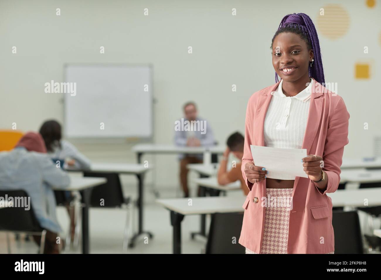 Portrait of teenage African-American girl in school classroom smiling ...