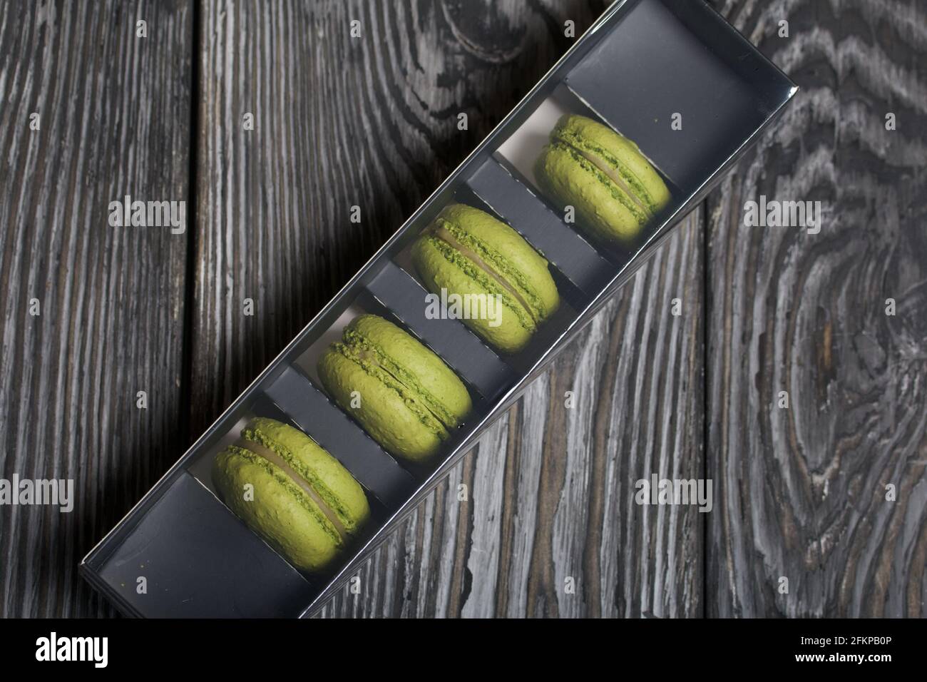 Macarons cakes light green color. Packaged in a black box. On black and ...