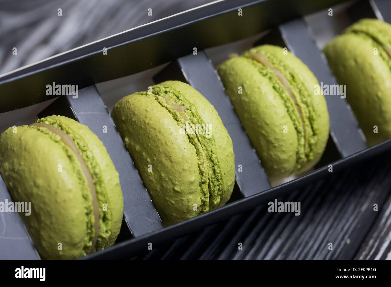 Macarons cakes light green color. Packaged in a black box. On black and ...