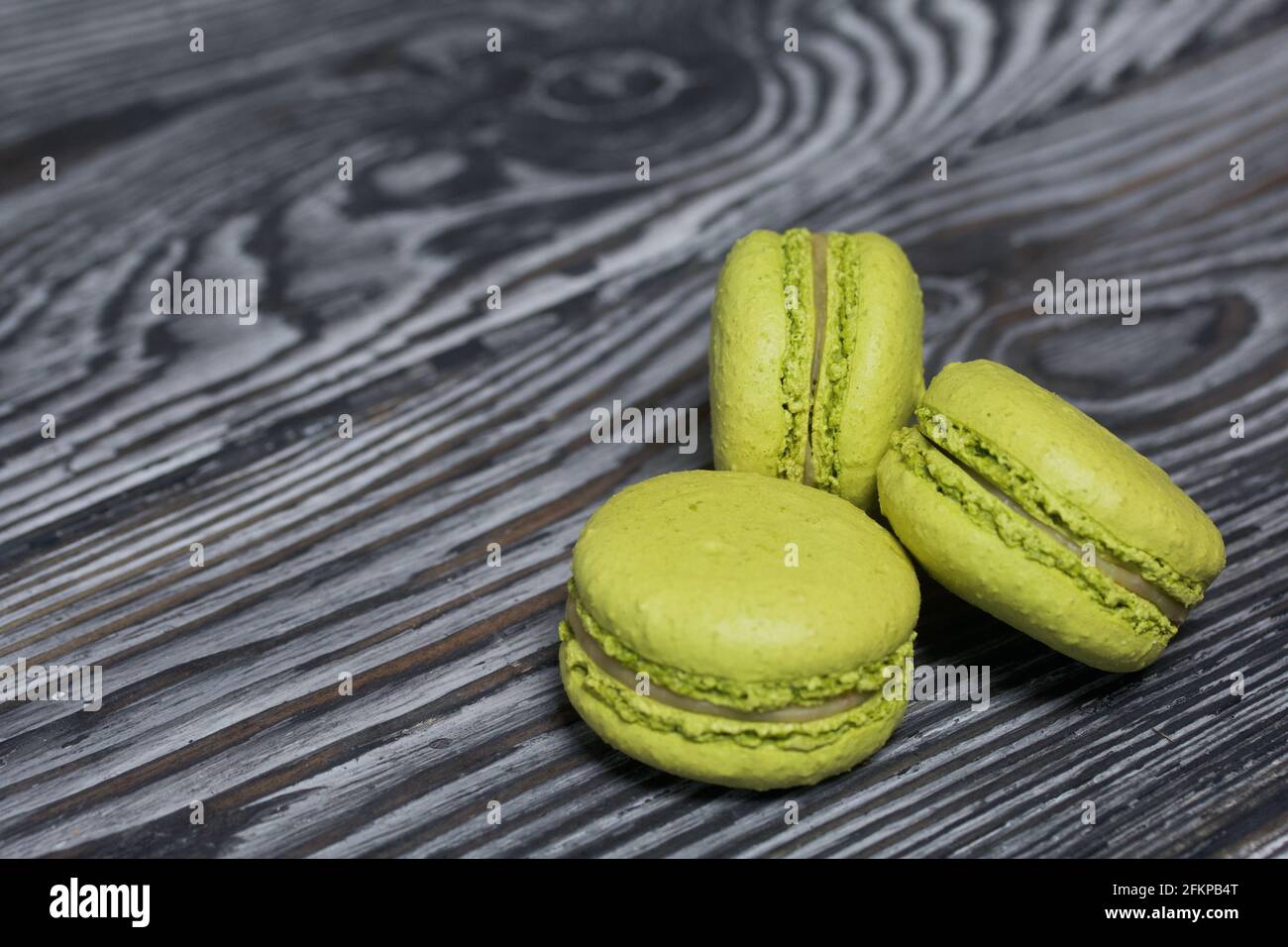 Macarons cakes light green color. They lie on black and white pine ...
