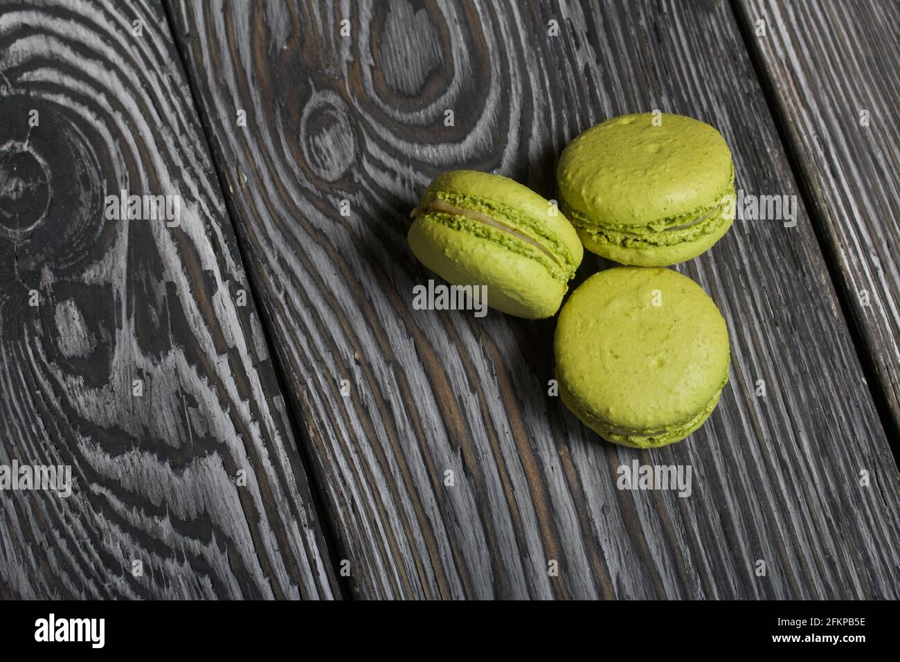 Macarons cakes light green color. They lie on black and white pine ...
