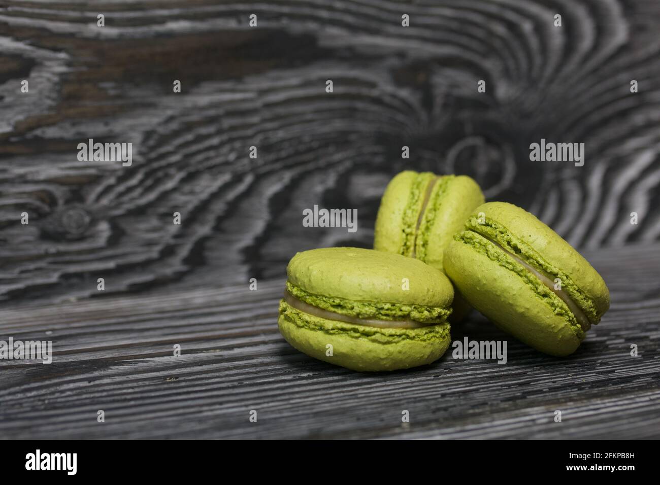 Macarons cakes light green color. They lie on black and white pine ...
