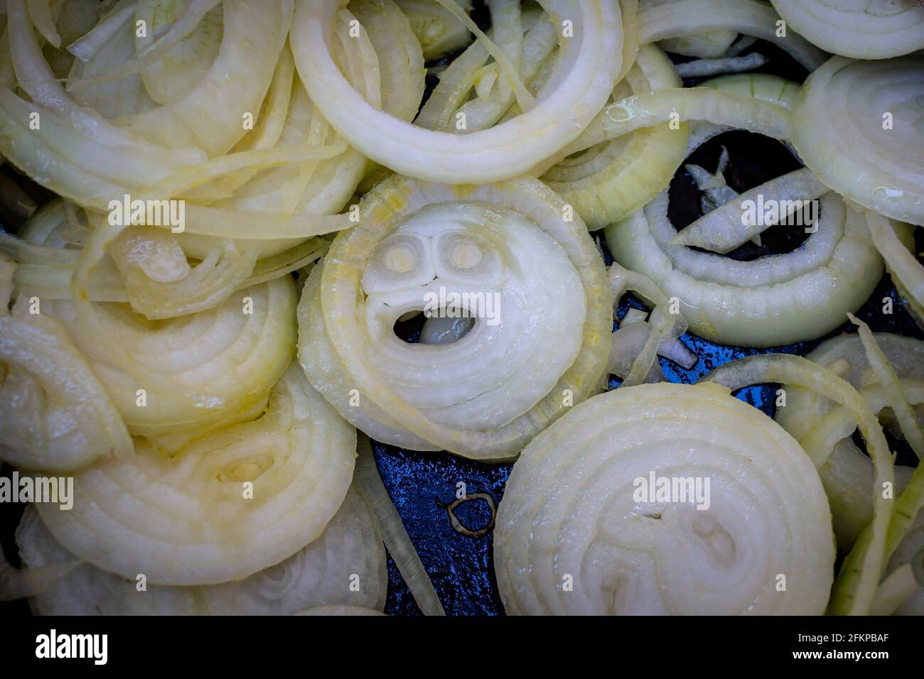 Chopped onions in a pan with one slice looking like a face Stock Photo ...