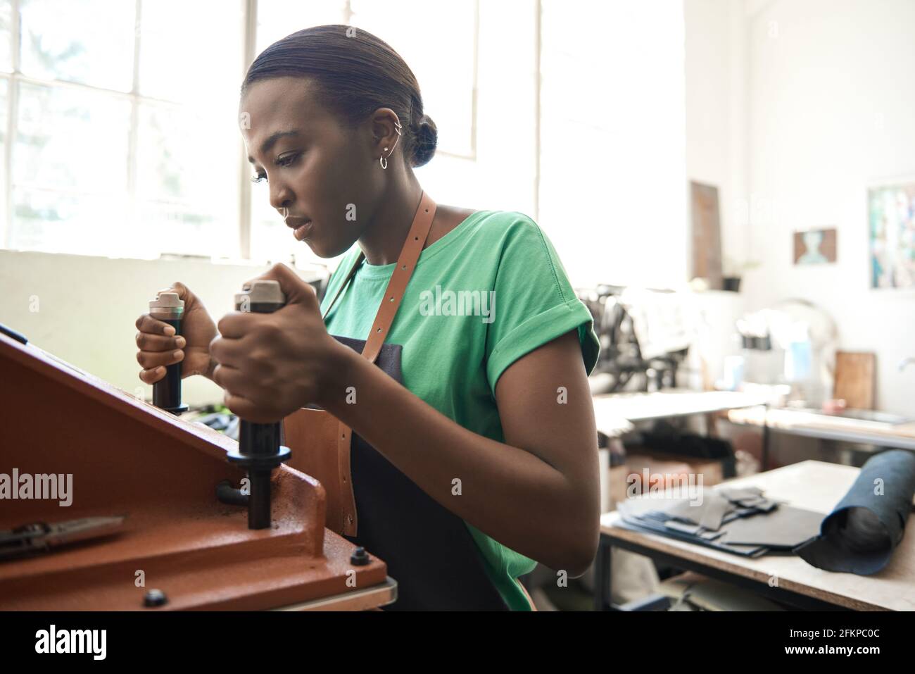Young African female leather worker using a cutting machine Stock Photo ...