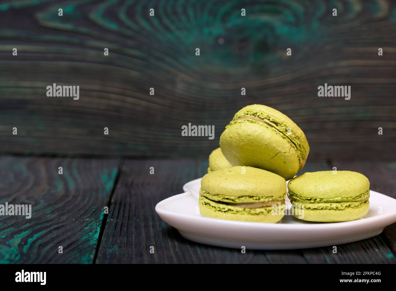 Light green macarons lie on a saucer. On pine planks with a crisp woody ...