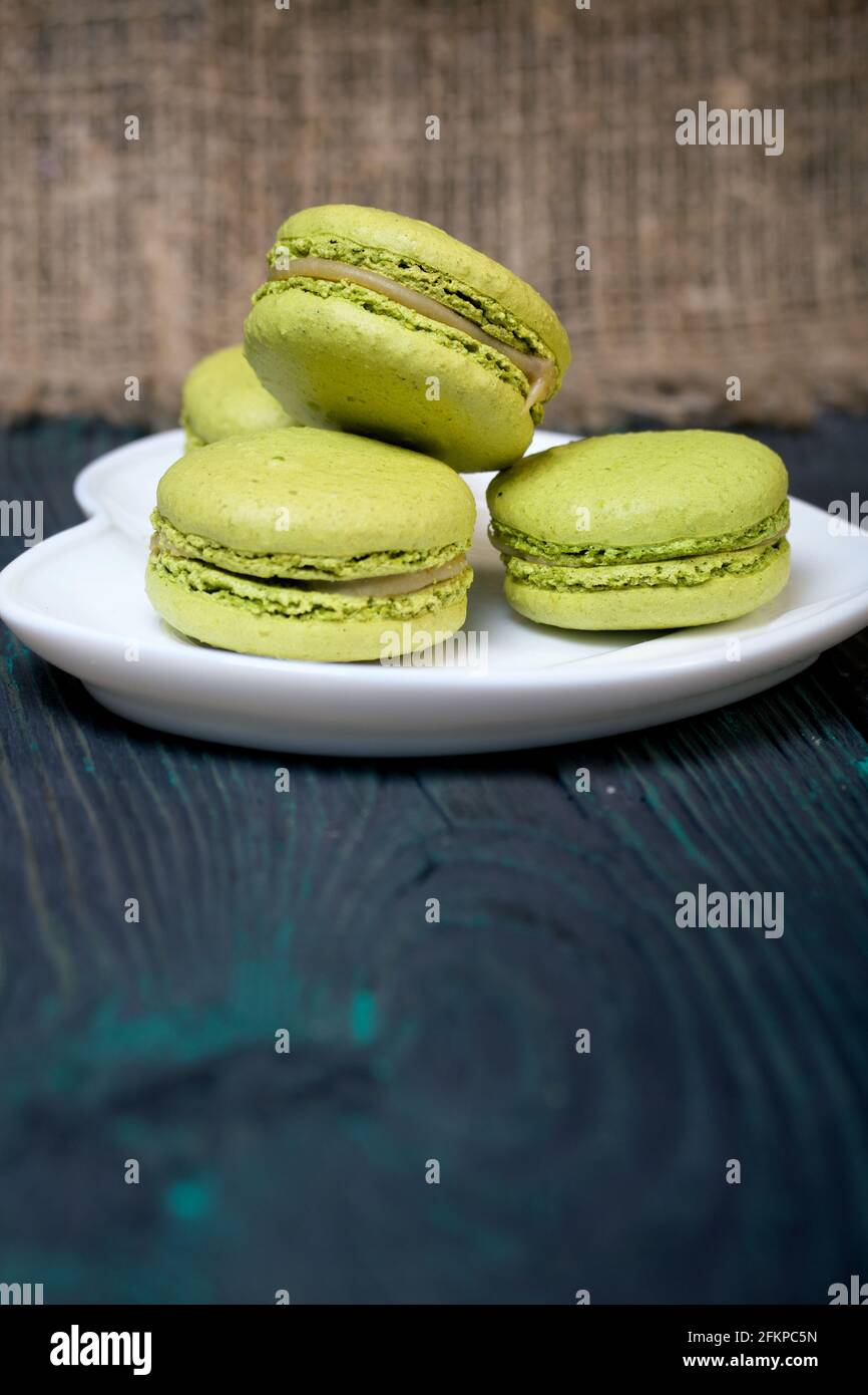 Light green macarons lie on a saucer. On pine planks with a crisp woody ...