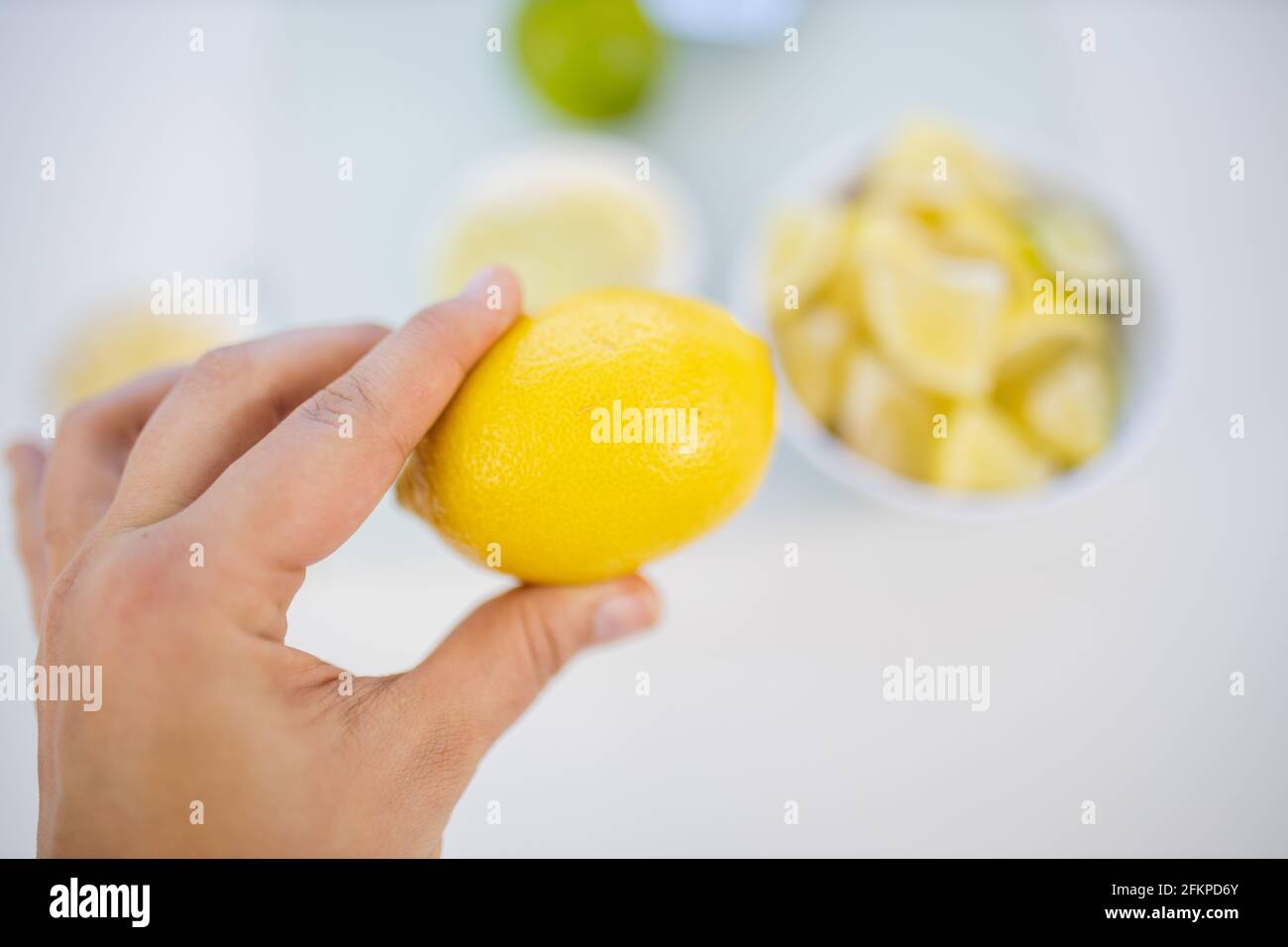 Female hand holding a lemon above slices of limes and lemons Stock ...
