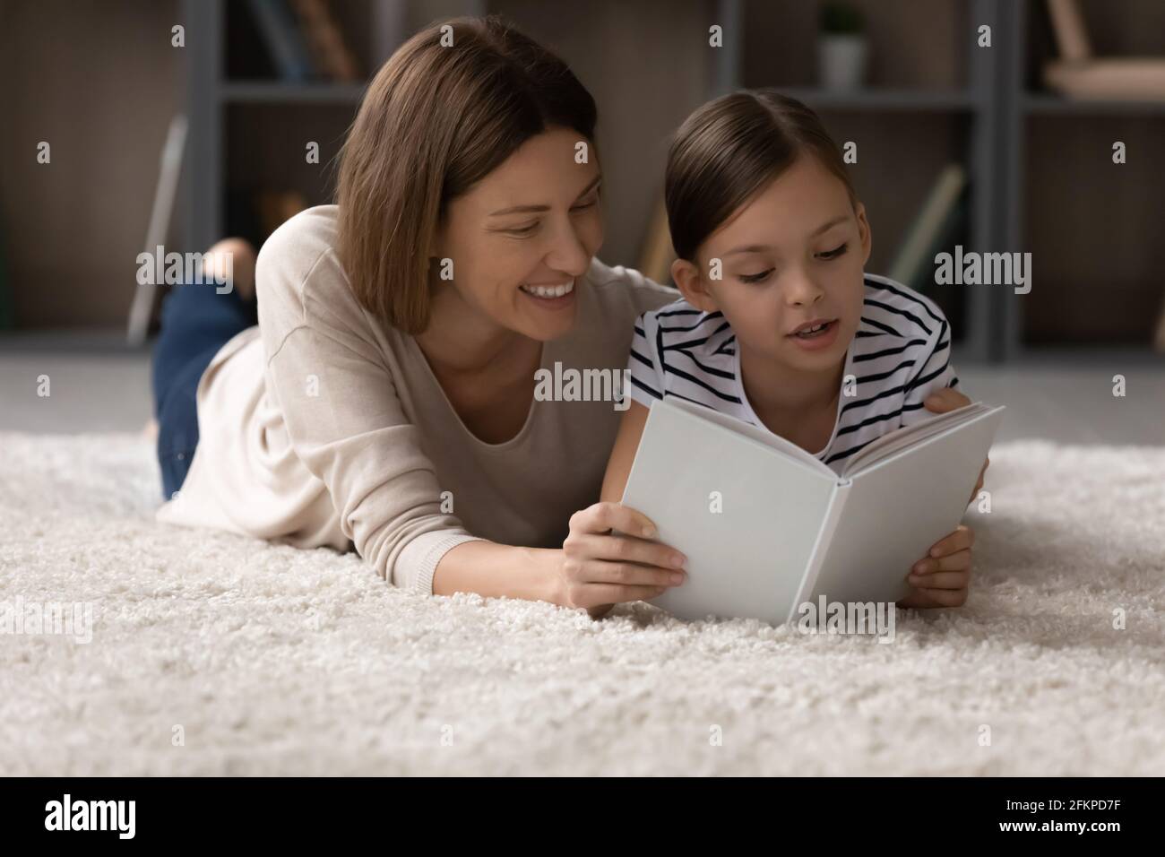 Happy mother and small daughter reading book together Stock Photo - Alamy
