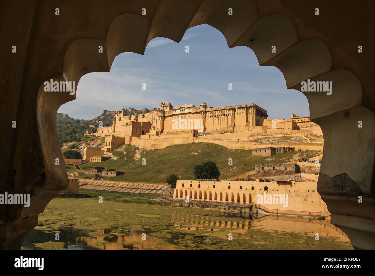 View of the Amber Fort through an ornate archway. Located on a hilltop ...
