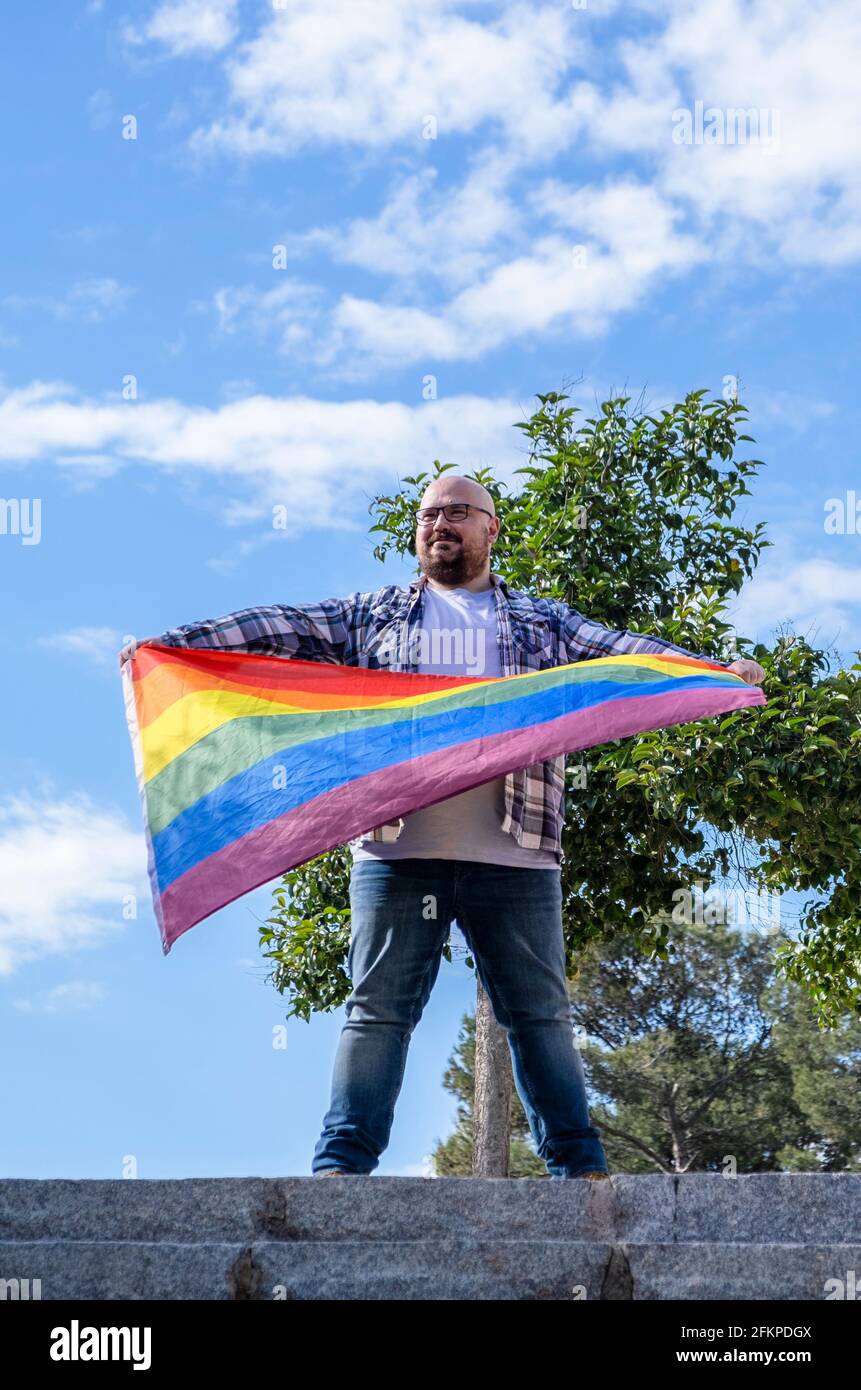A boy holding the rainbow flag, blowing in the wind. Gay love. Gay ...