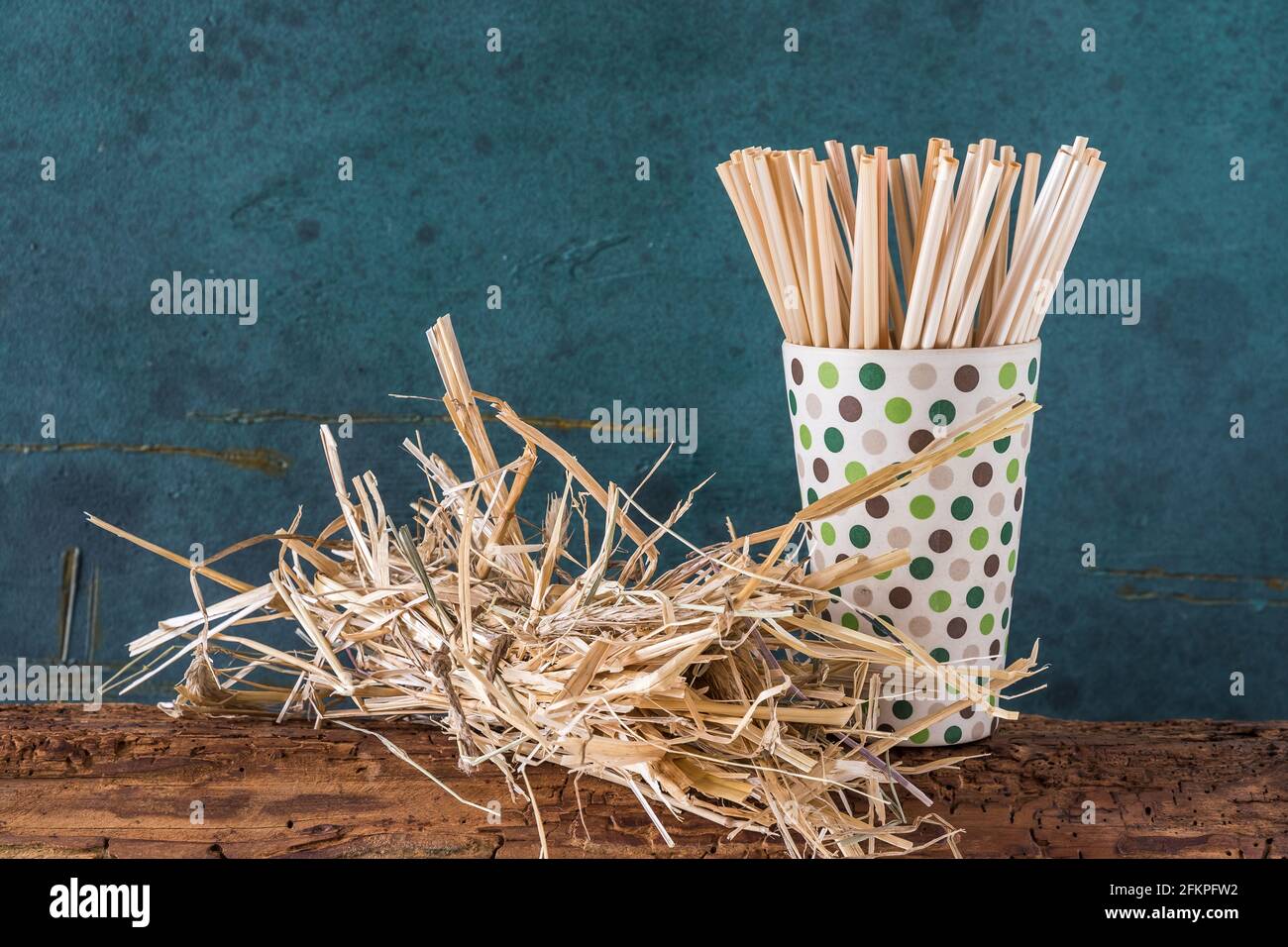 Natural straw drinking straws in a bamboo beaker and a bundle of straw ...