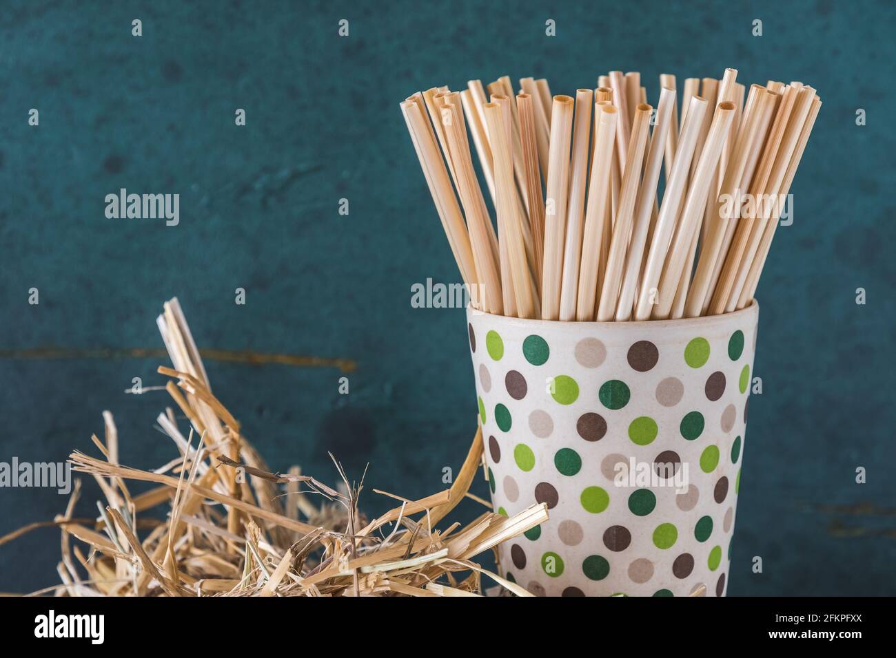 Natural straw drinking straws in a bamboo beaker and a bundle of straw ...