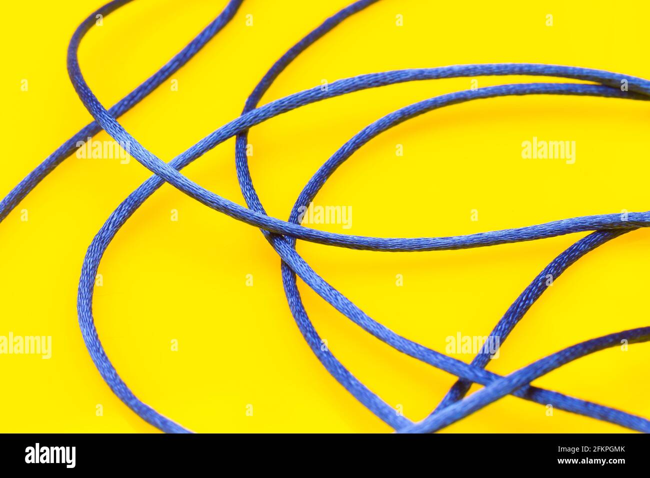 Thin blue string on yellow background, messy thread off the spool ...