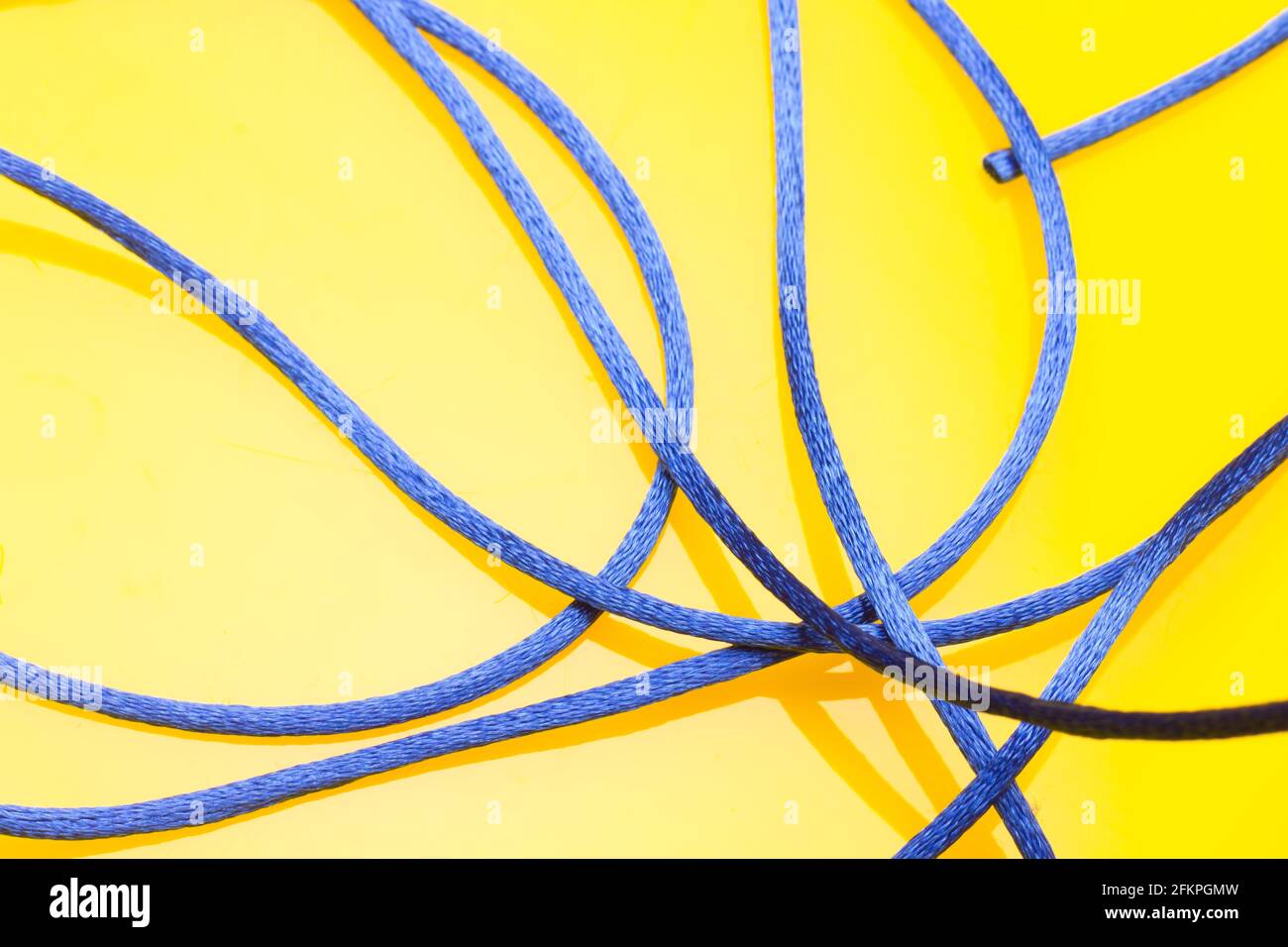 Thin blue string on yellow background, messy thread off the spool ...