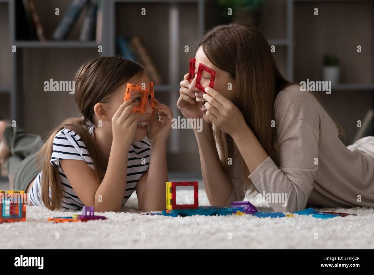 Smiling mom and little daughter play together Stock Photo - Alamy