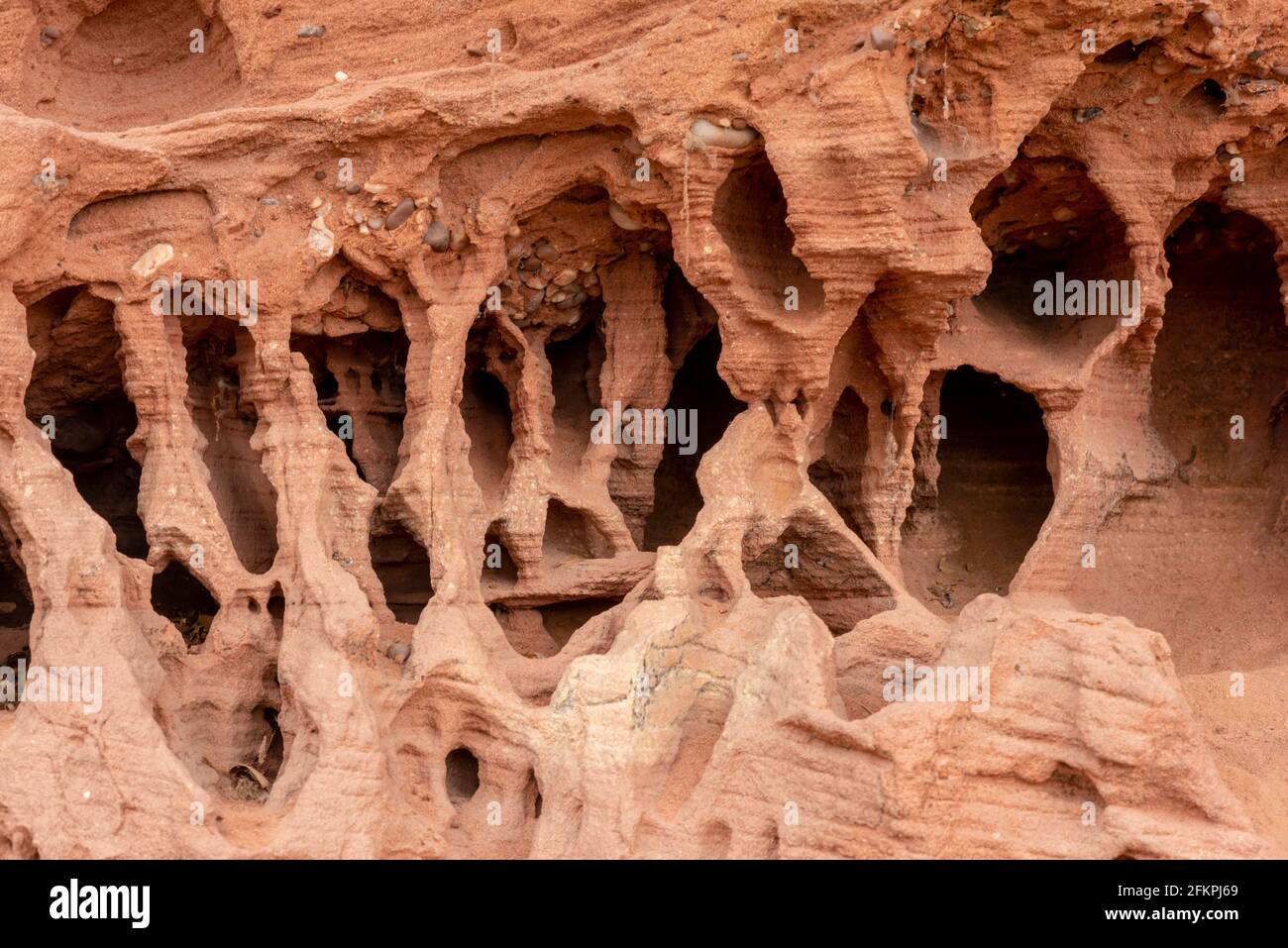 Red sandstone rocks washed out by the water with deep furrows and ...