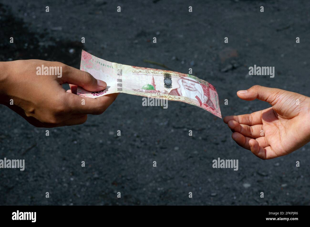 Asian children's hand with 100 Riyal, the currency of Saudi Arabia ...