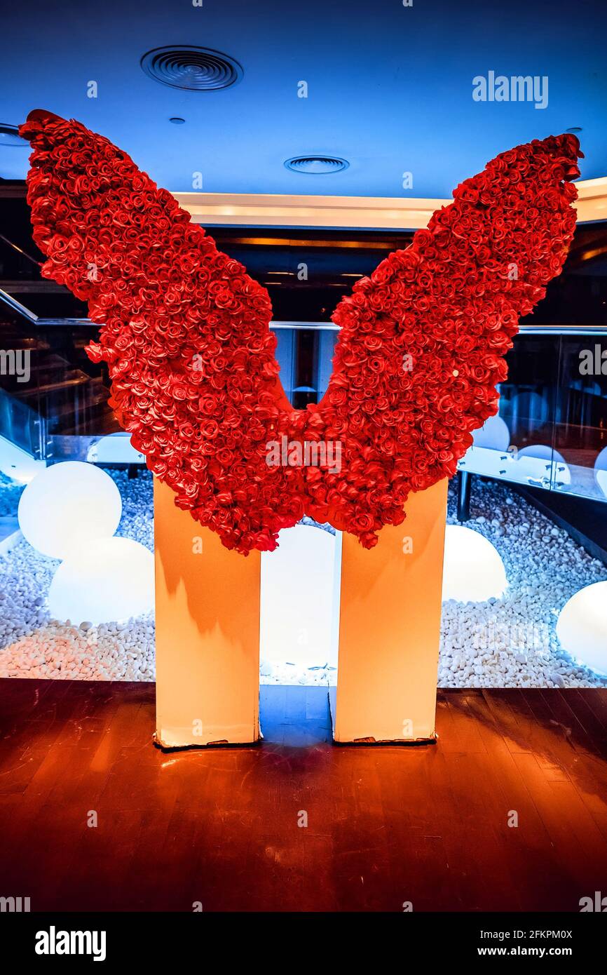 Large wings of red roses on a pedestal, white round lamps in the ...