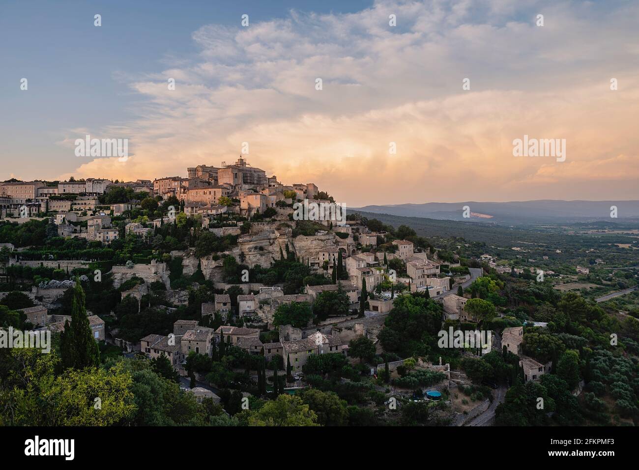Gordes village on a hill at sunset with the valley in the background ...