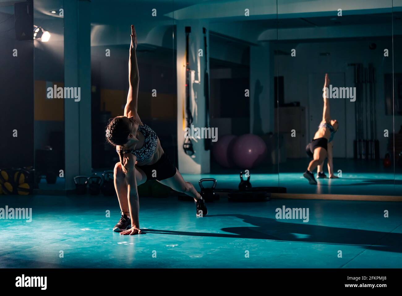 A young woman is stretching in the gym through an exercise in a ...