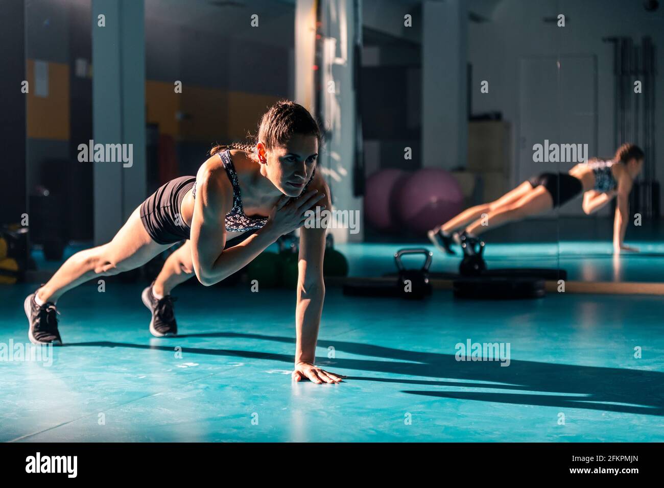 A young female workout in the gym and doing a shoulder taps exercise ...