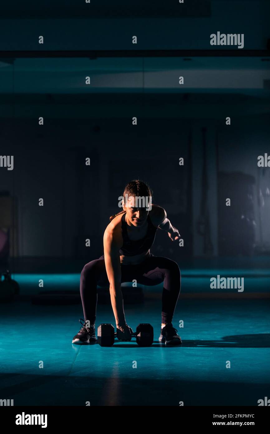 A fit young woman doing a dumbbell snatch exercise in the gym Stock ...
