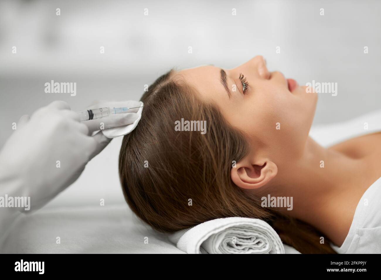 Side view of young brunette woman on procedure for improvements hair ...