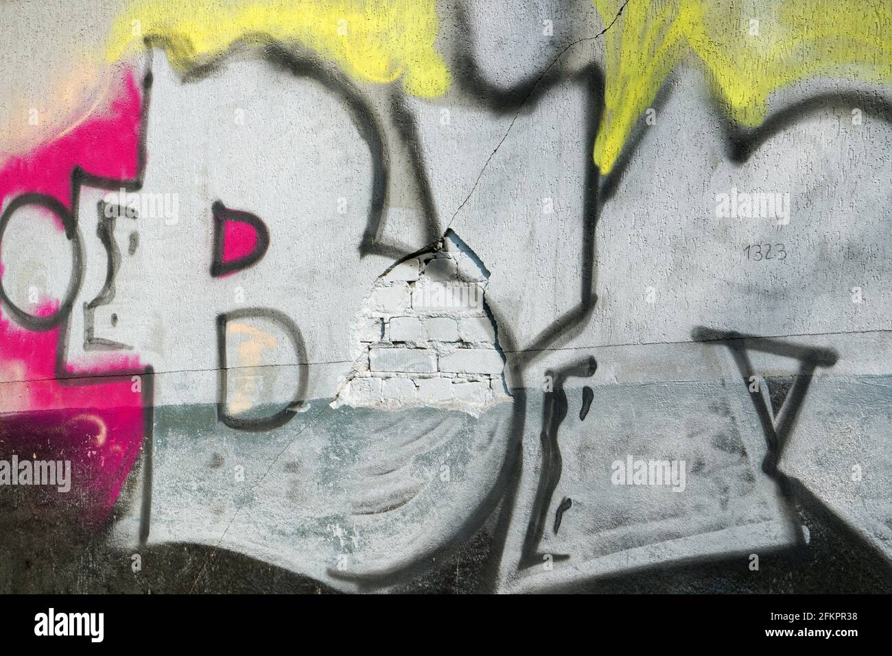 Graffiti sprayed wall of a building with cracks and crumbling plaster ...