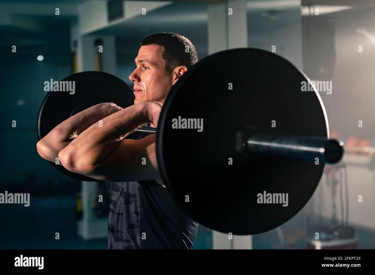 A fit man standing in the gym with weights on and doing an exercise ...