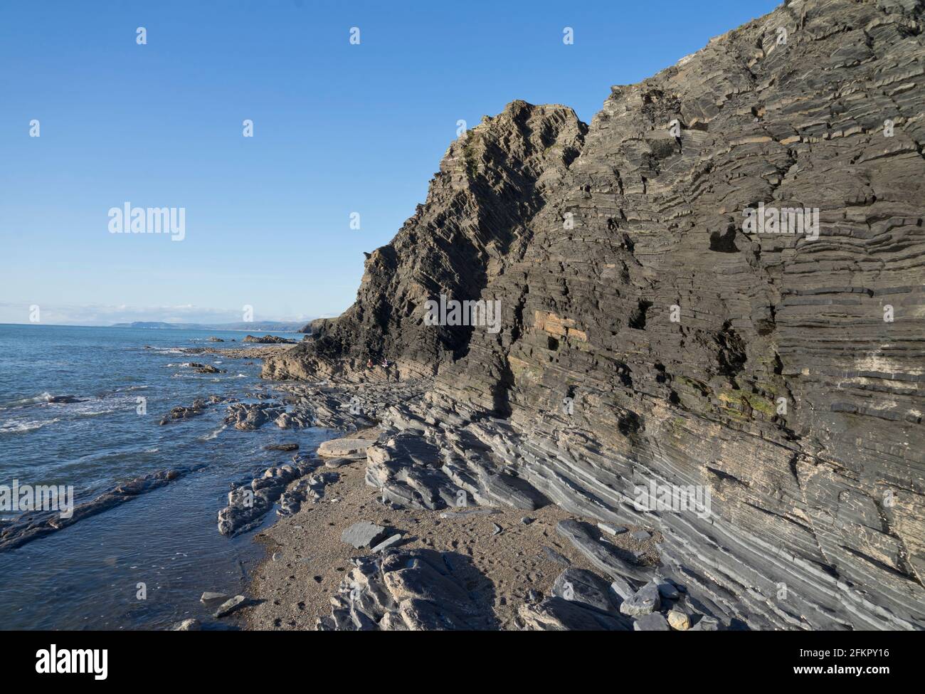 Beach with pebbles,rocks and stacked limestone strata in Ceredigion ...